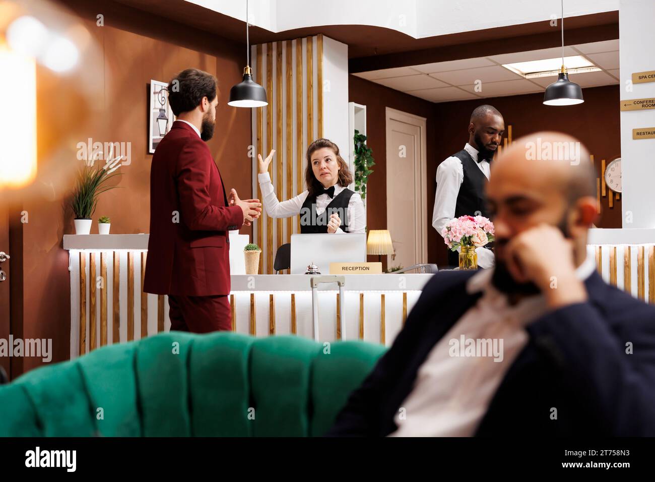 Businessman chats with front desk staff in reception lobby, asking ...