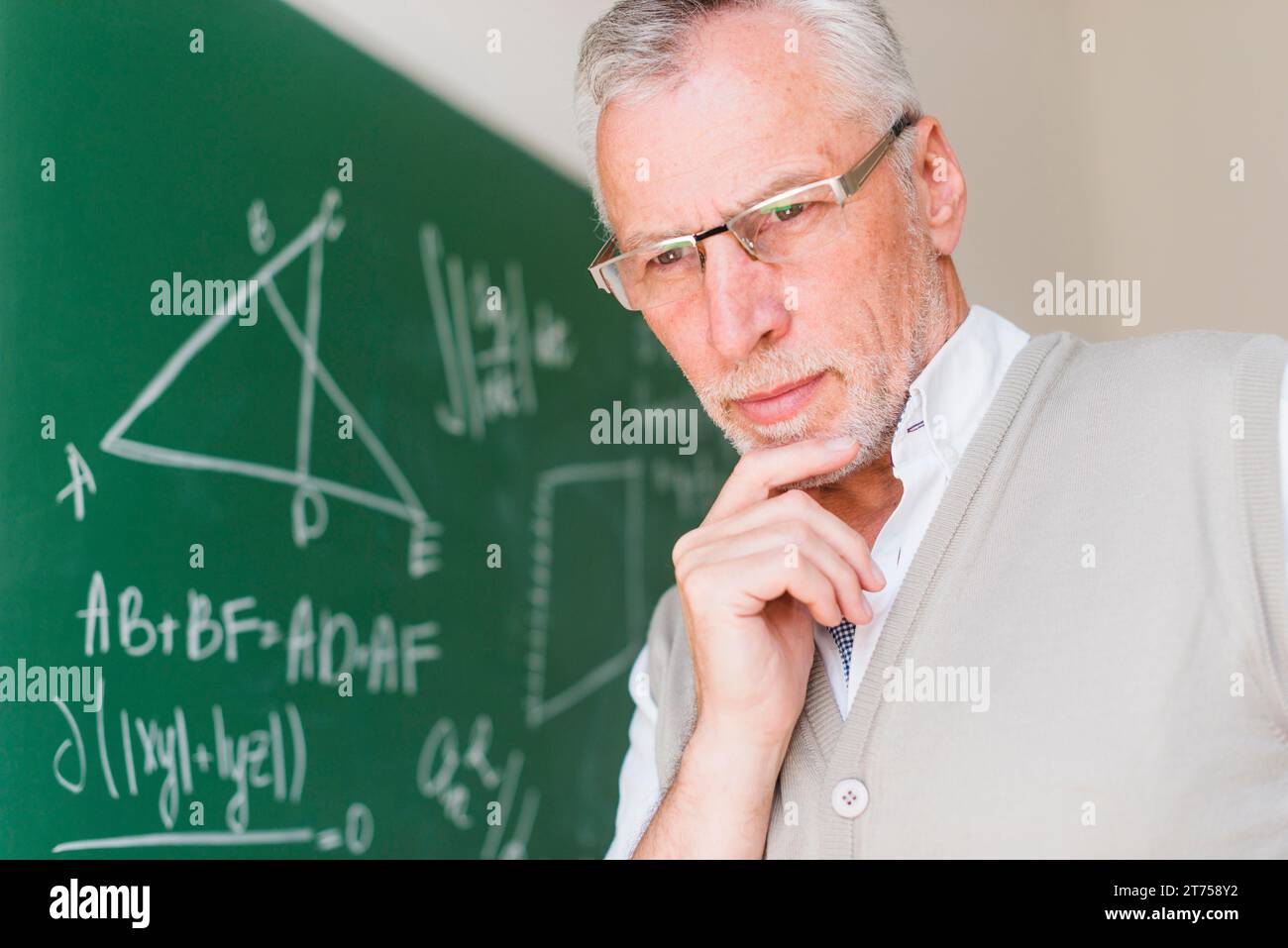 Aged professor standing near chalkboard classroom Stock Photo - Alamy