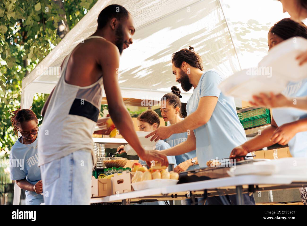 Multicultural team of charity workers serving nourishments to refugees ...