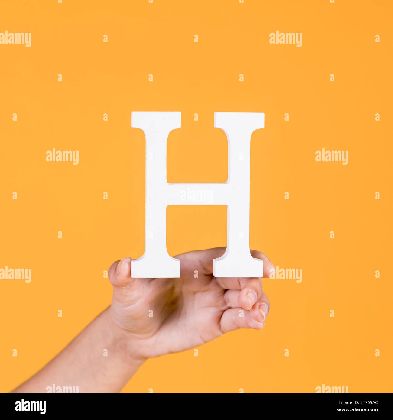 Close up human hand holding up uppercase capital letter h yellow ...