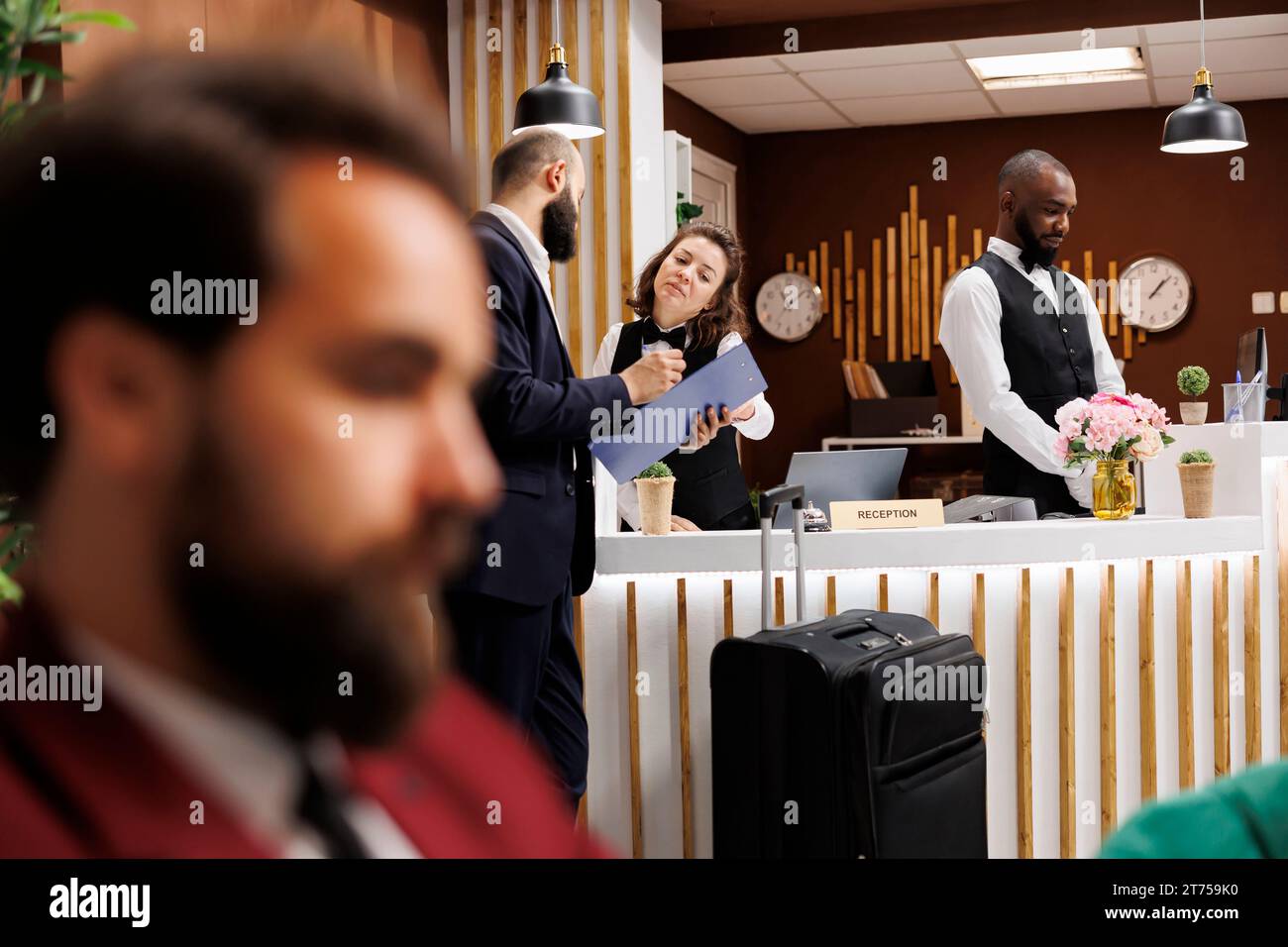 Hotel receptionist doing check in for businessman at front desk ...