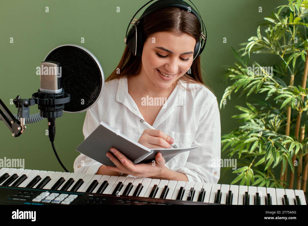 Front view smiley female musician playing piano keyboard writing songs ...