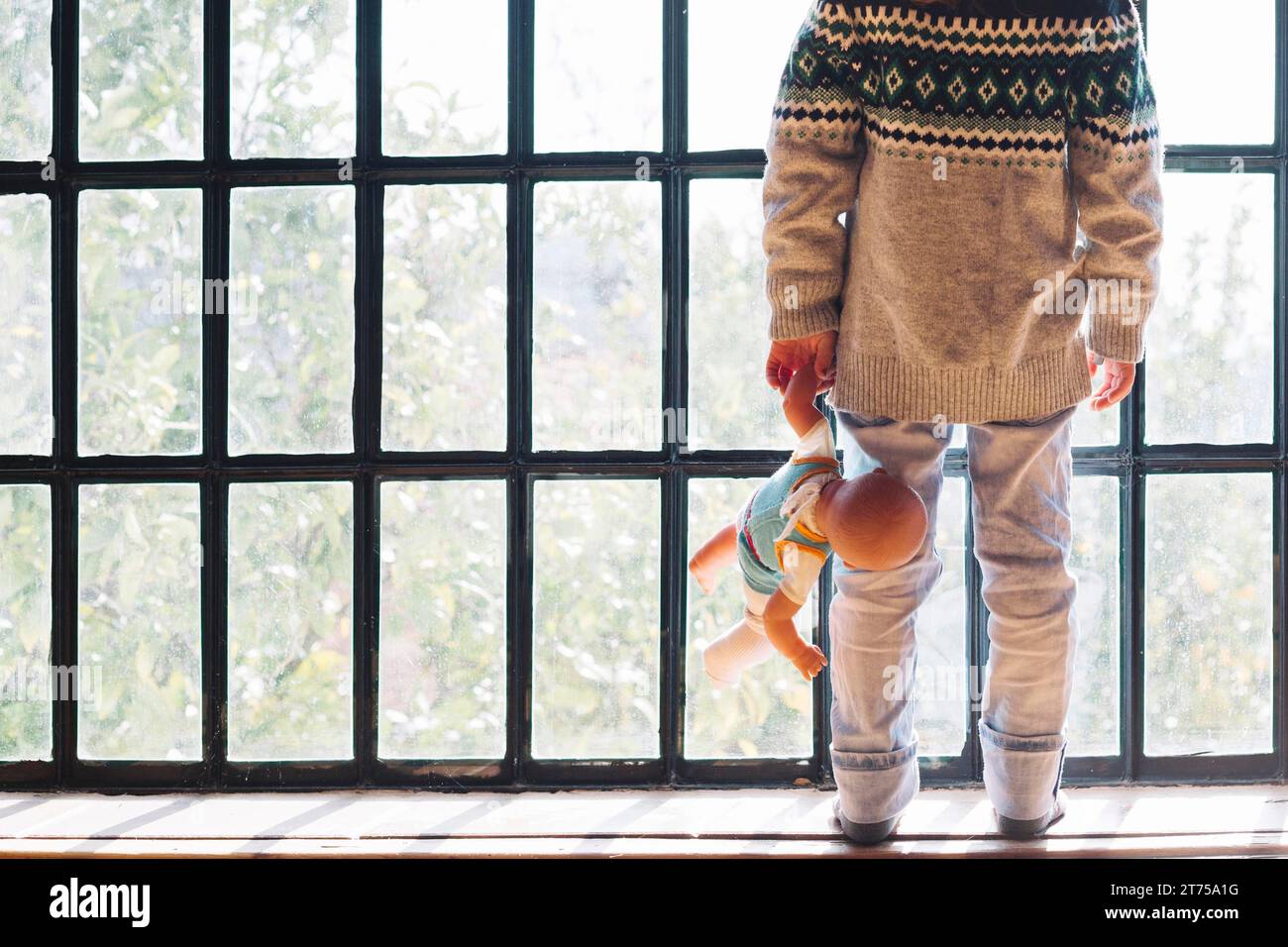 Girl standing front window with doll Stock Photo - Alamy