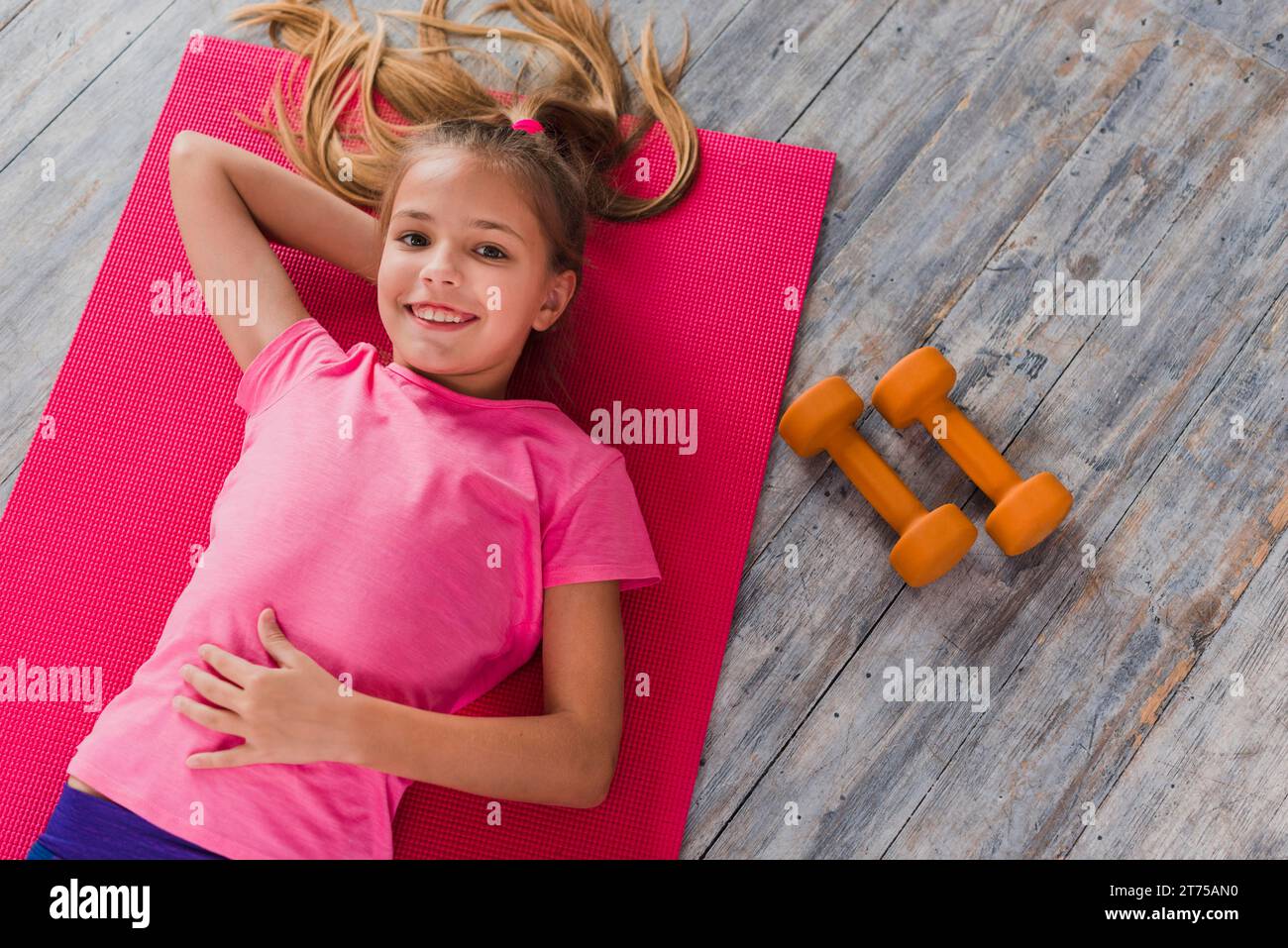 Overhead view girl lying exercise mat near dumbbell Stock Photo - Alamy