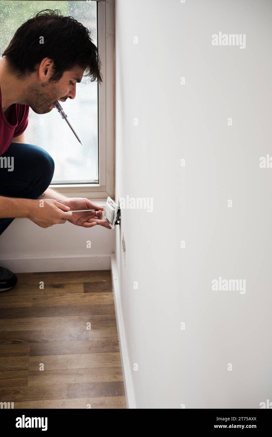 Side view male electrician fixing plug white wall Stock Photo - Alamy