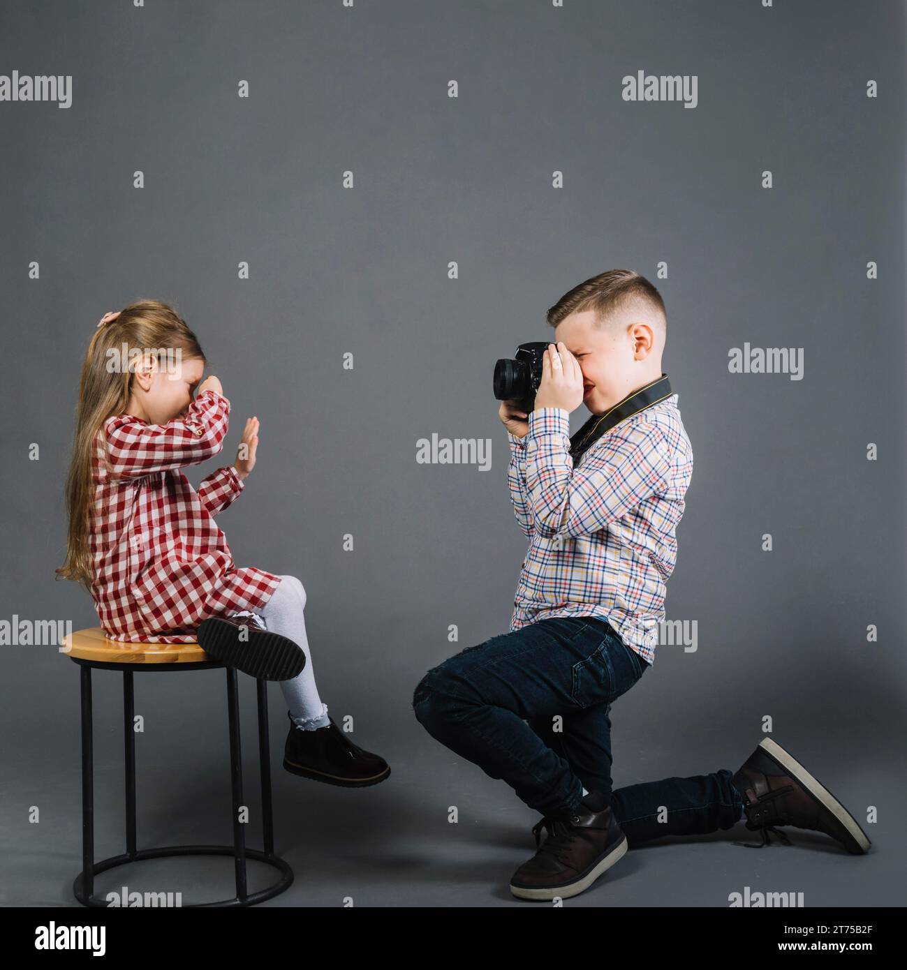 Side view boy taking girl sitting stool with camera Stock Photo - Alamy