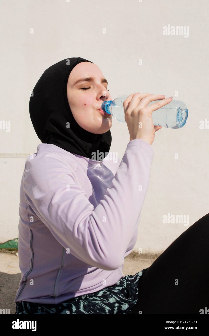 Woman with purple jacket drinking water Stock Photo - Alamy