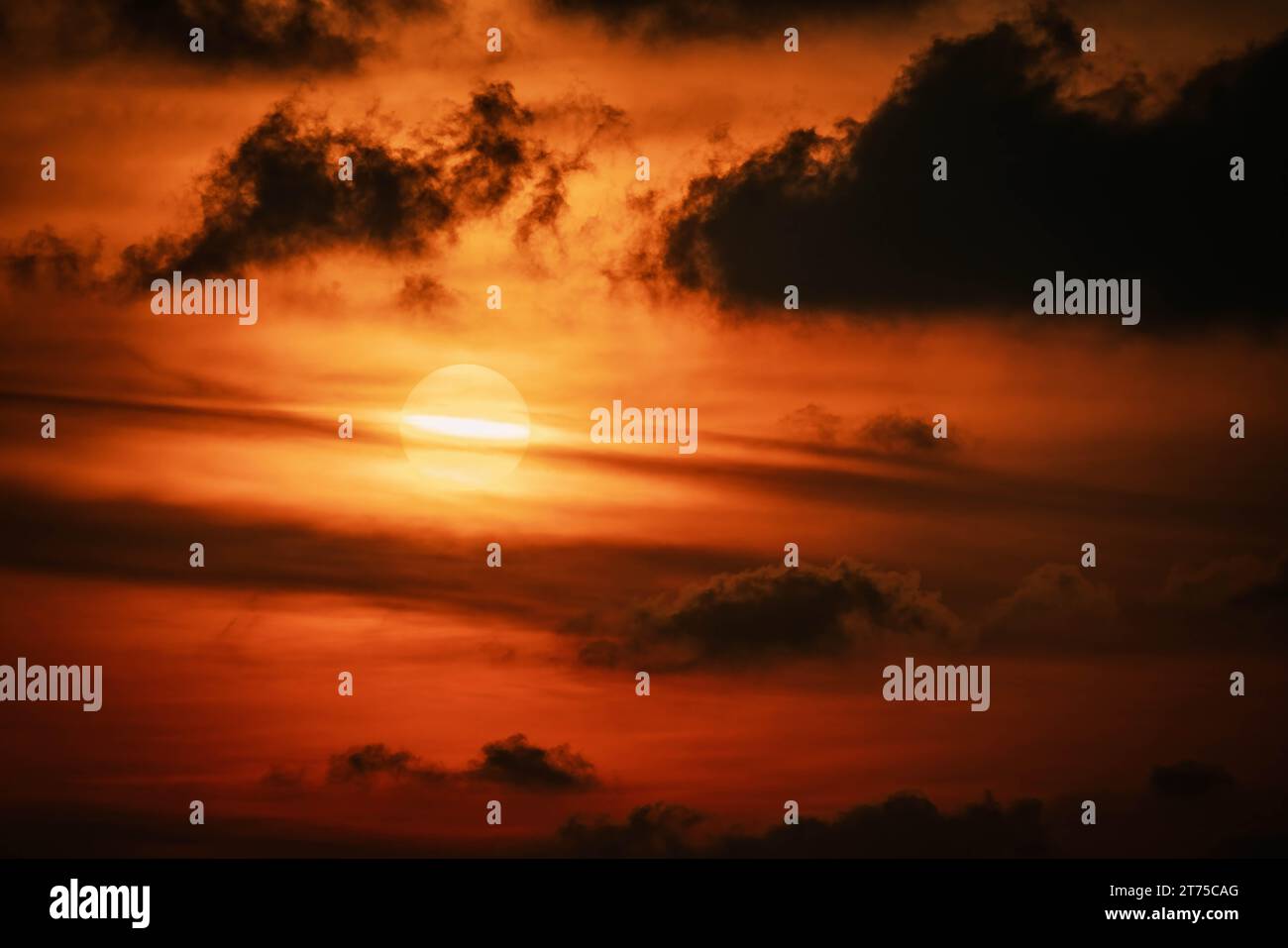 Scenic red orange Sunset with Sun hiding in clouds, glowing light line ...