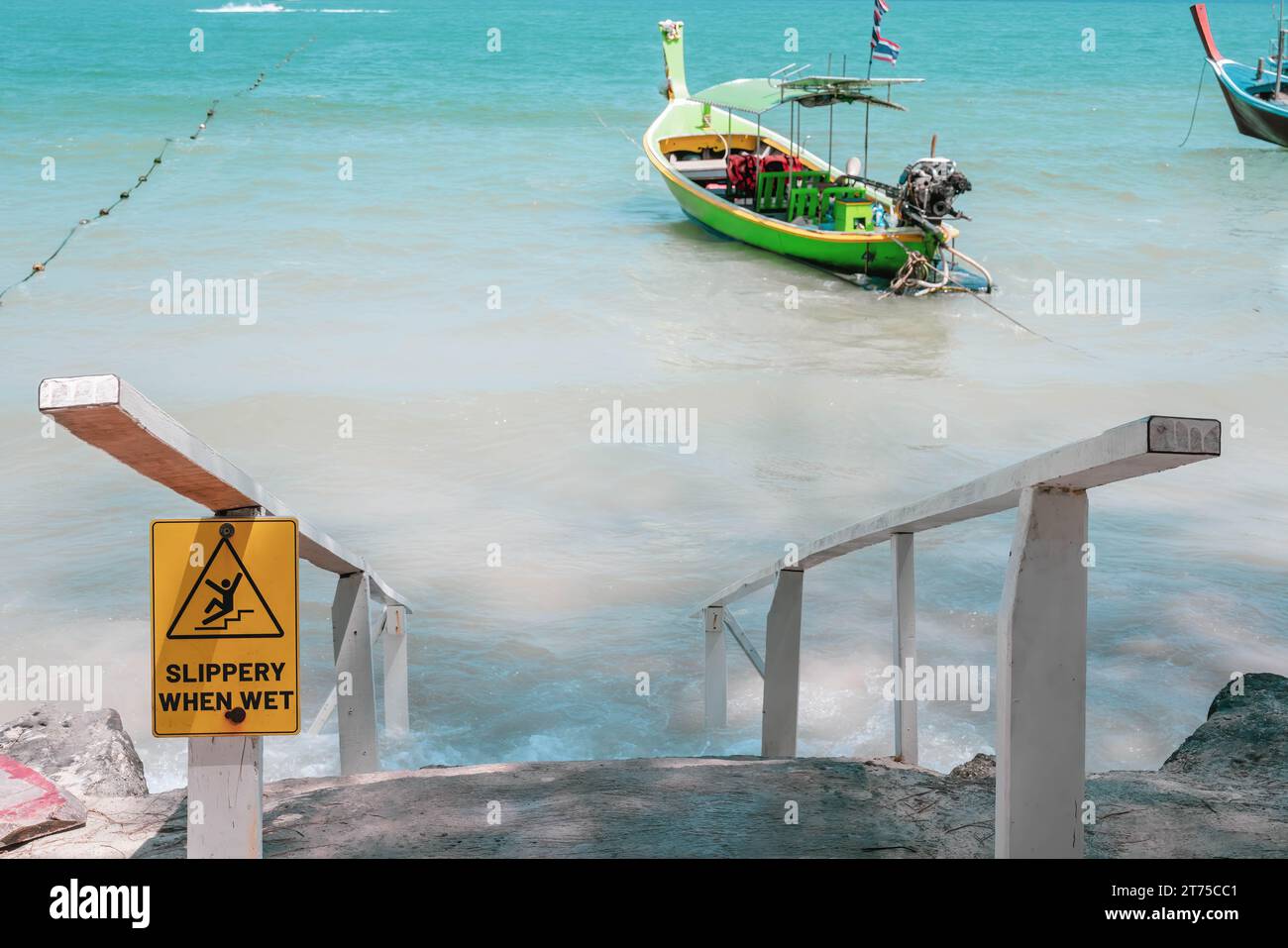 Down stairs to seashore with warning sign - slippery when wet. Blurry ...