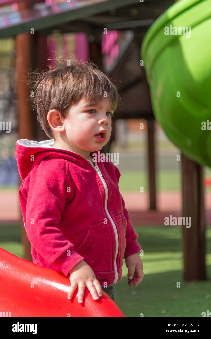 Little boy looks confused while standing outdoors on the playground ...