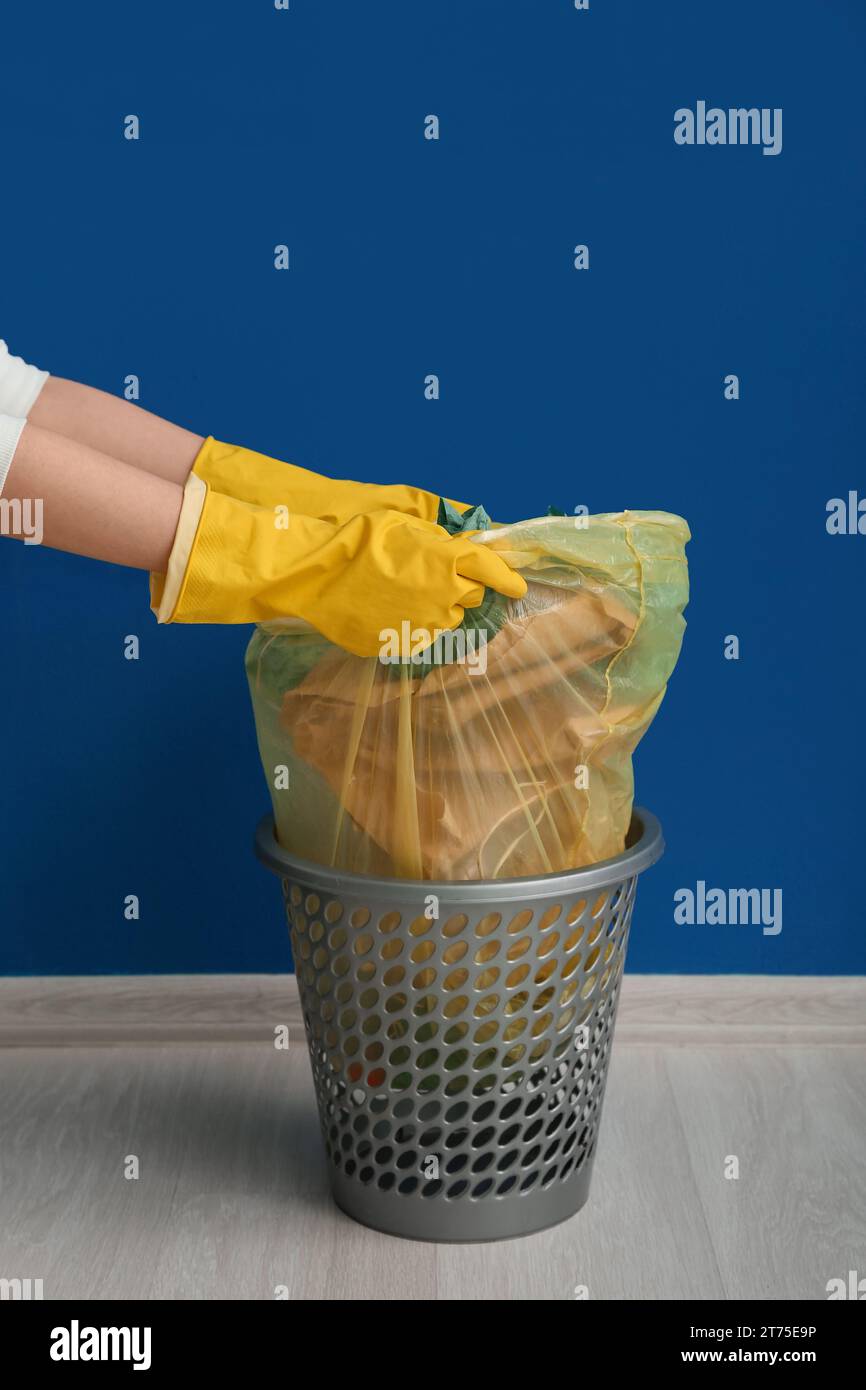 Female hands in rubber gloves pulling full garbage bag from trash bin ...