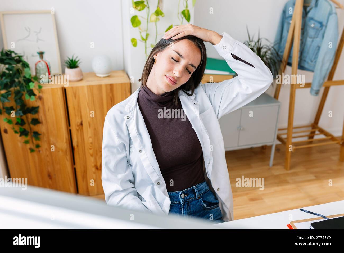 Young female doctor stretching her body while working on computer at ...
