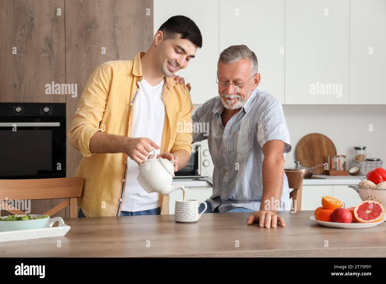 Young man pouring hot tea for his father in kitchen Stock Photo - Alamy
