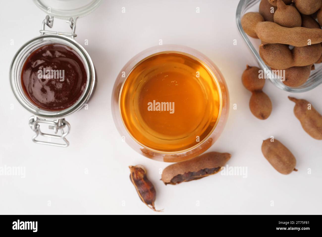 Glass of tasty tamarind drink with jam and fruits on white background ...