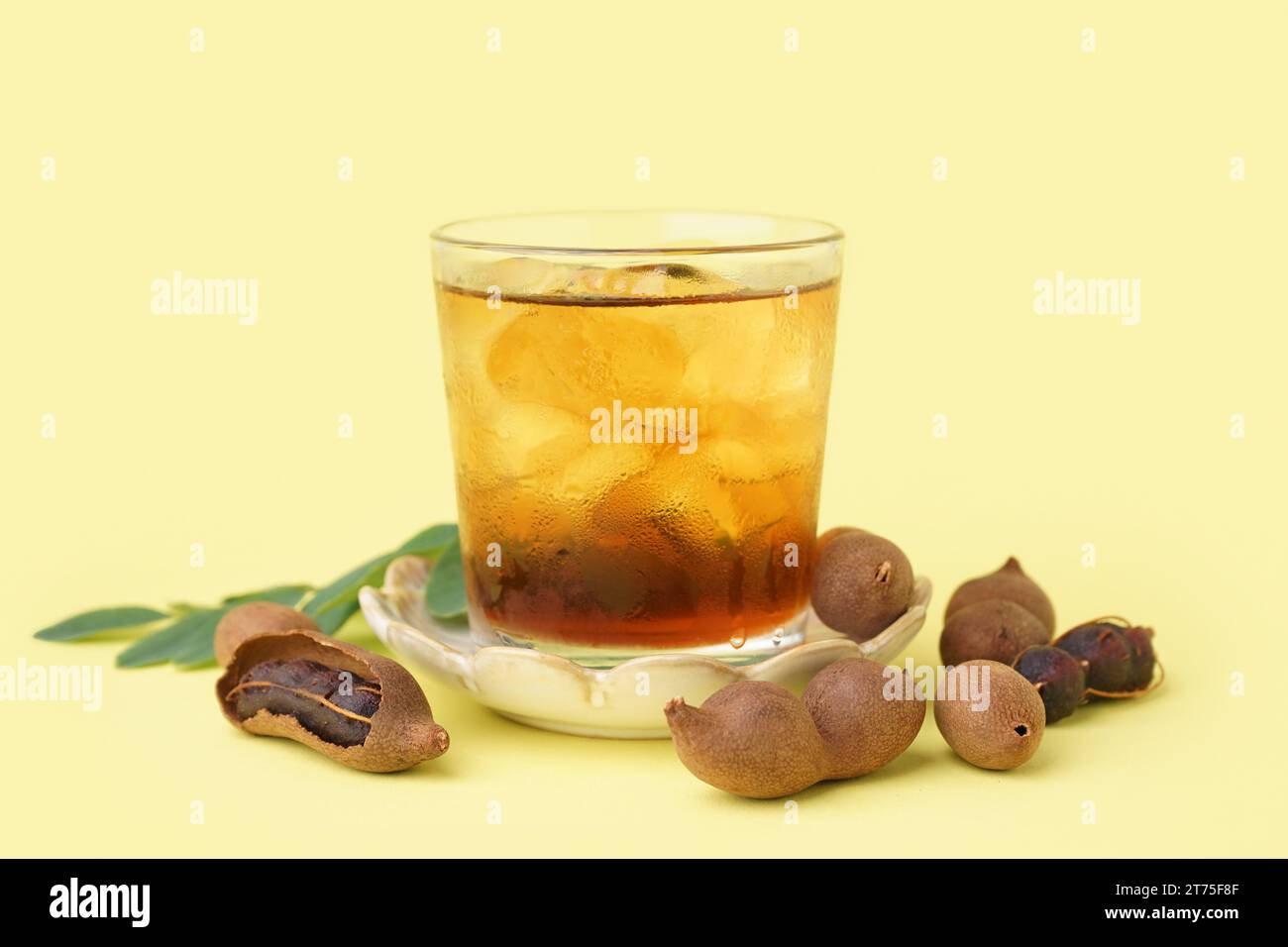 Glass of tasty tamarind drink and fruits on yellow background Stock ...