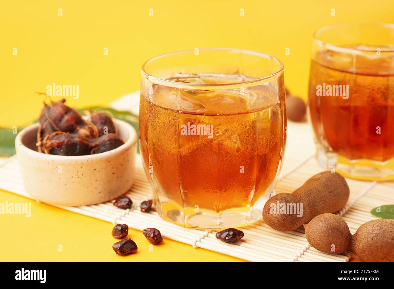 Glasses of tasty tamarind drink and fruits on yellow background Stock ...
