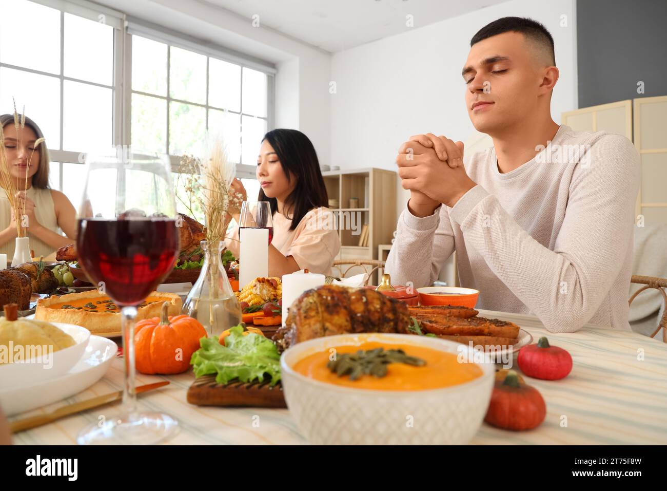 Group of young friends praying before dinner at festive table on ...