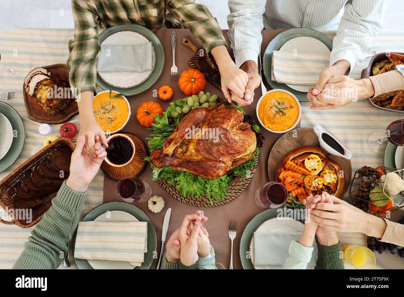 Happy family praying before dinner at festive table on Thanksgiving Day ...
