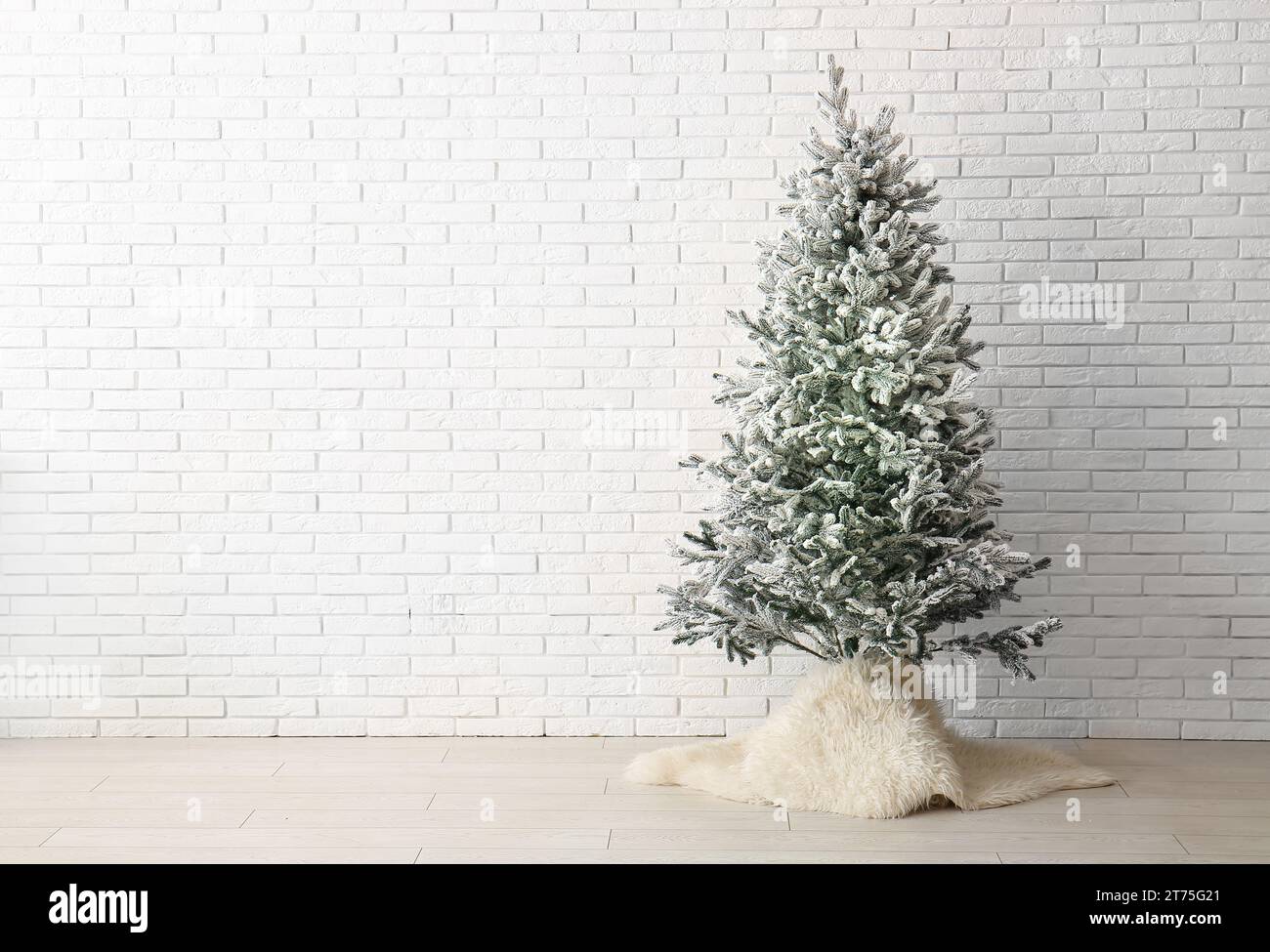 Beautiful Christmas tree near white brick wall Stock Photo - Alamy