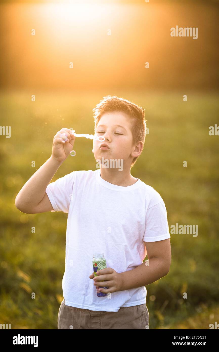Cute little boy is playing with big soap bubbles outdoor. Child is ...