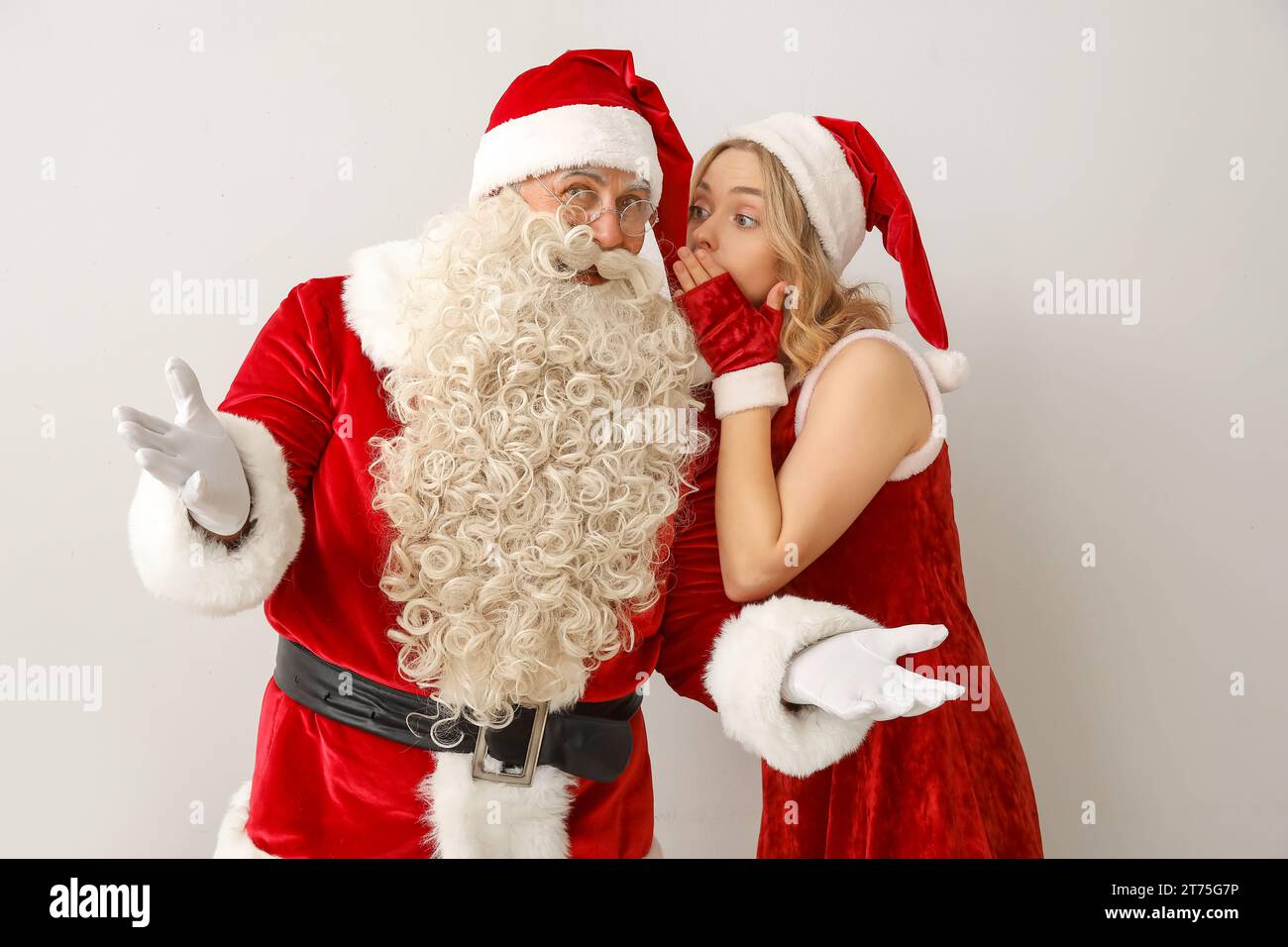 Beautiful woman telling secret to Santa Claus on white background Stock ...