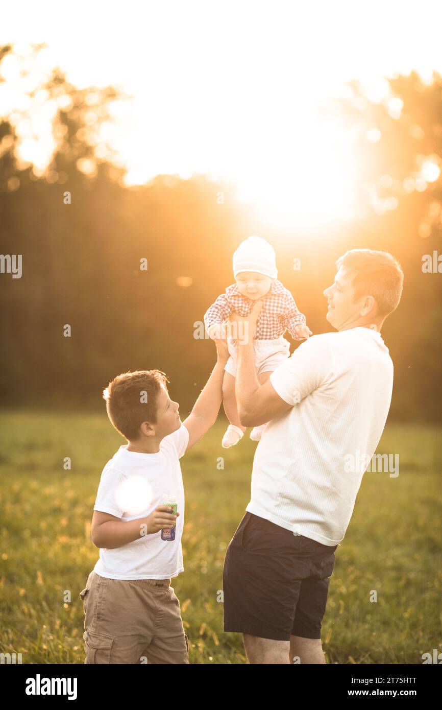 Happy family hugging and embracing on summer walk. Father and his two ...