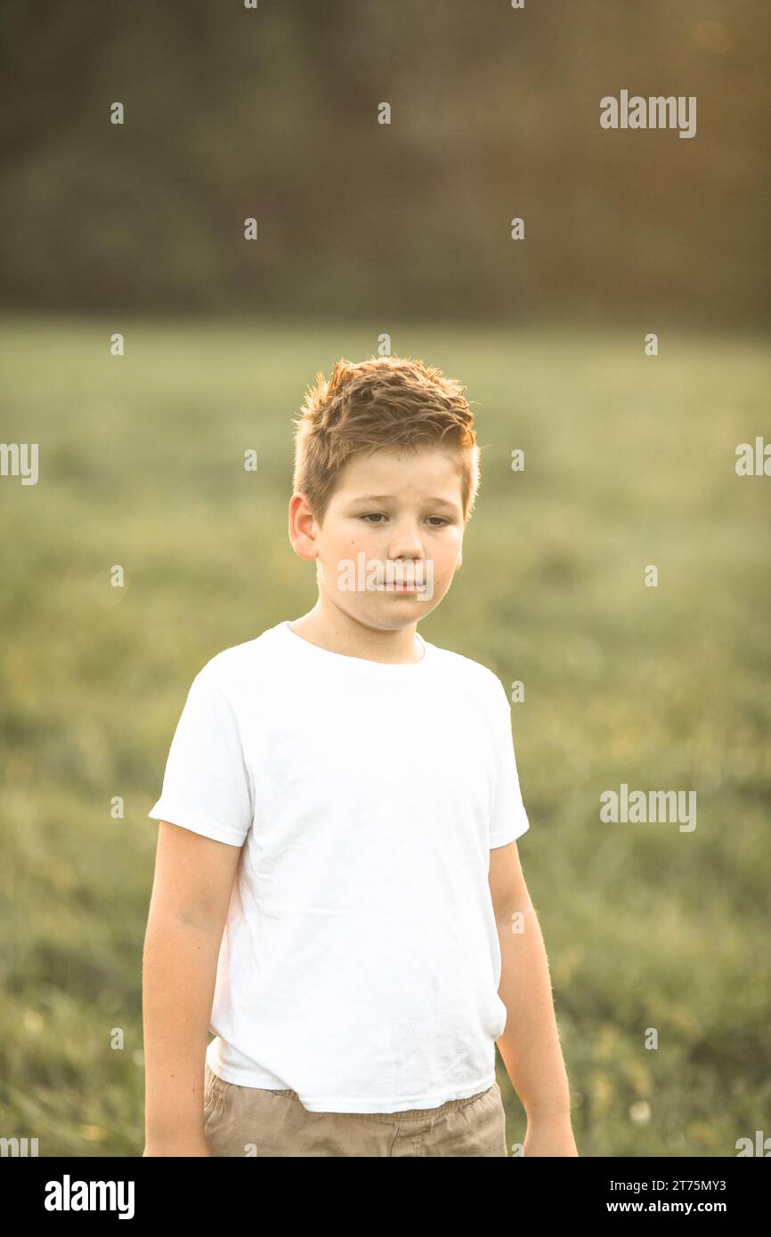 Upset little American boy looks at camera with confused face stands ...