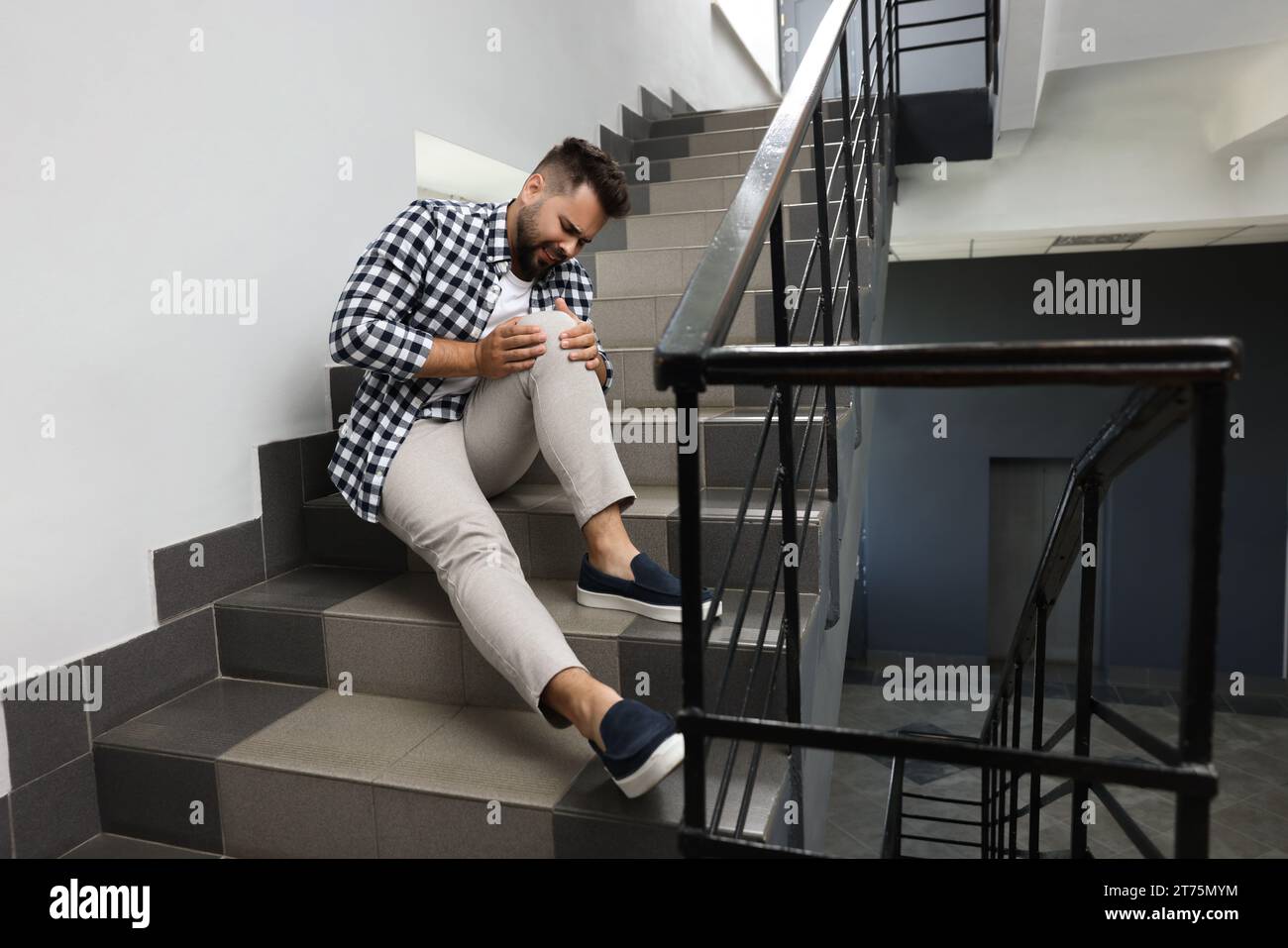 Man fallen down stairs suffering from pain in knee indoors Stock Photo ...