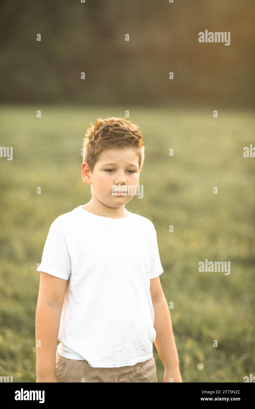 Upset little American boy looks at camera with confused face stands ...