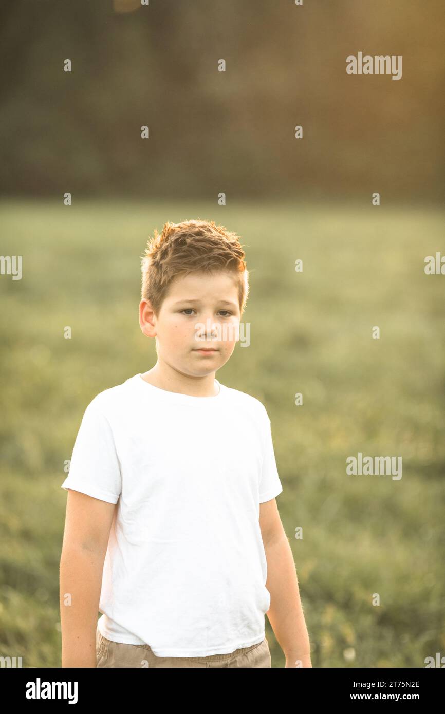Upset little American boy looks at camera with confused face stands ...