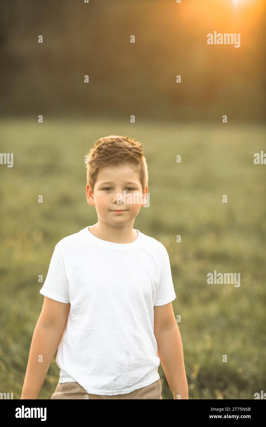 Upset little American boy looks at camera with confused face stands ...