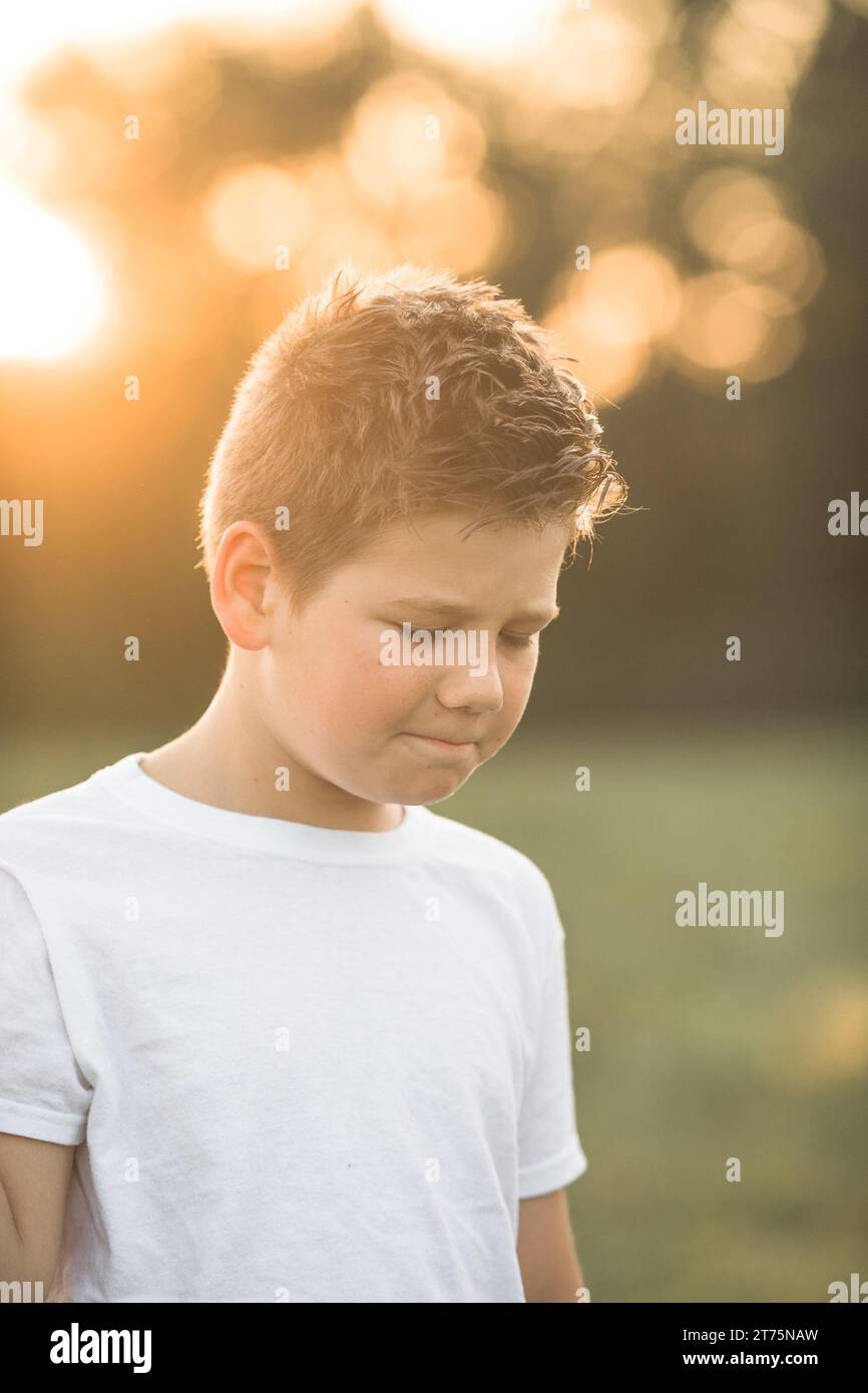 Upset little American boy looks at camera with confused face stands ...