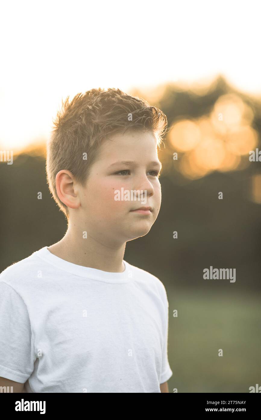 Upset little American boy looks at camera with confused face stands ...