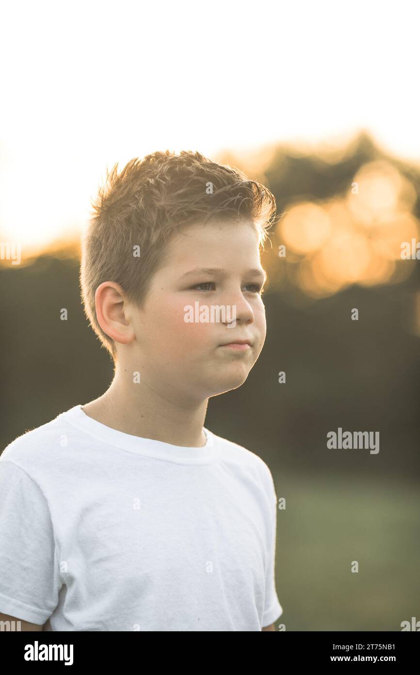 Upset little American boy looks at camera with confused face stands ...