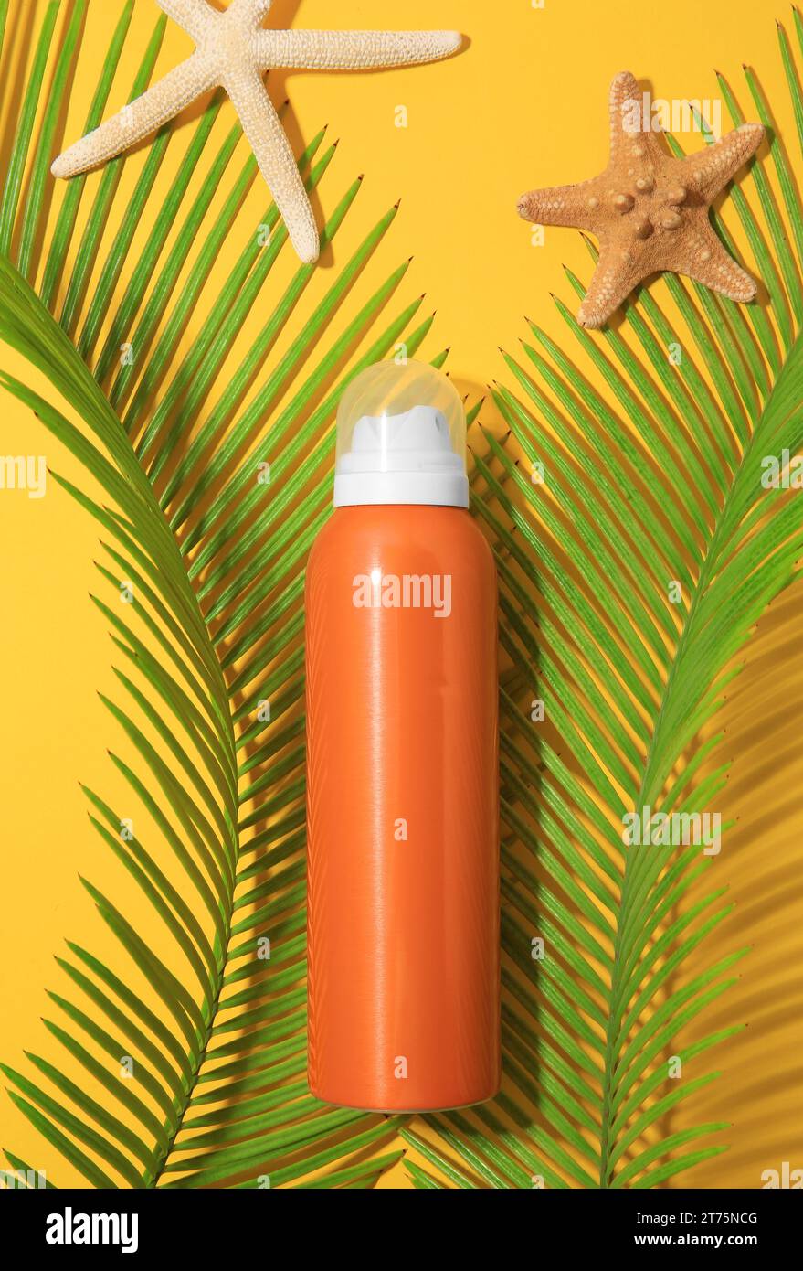 Sunscreen, sea stars and tropical leaves on yellow background, flat lay ...