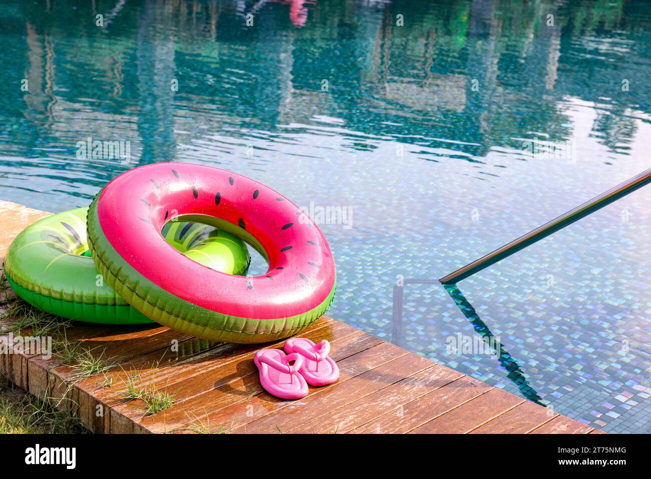 Inflatable rings and flip flops on wooden deck near swimming pool ...