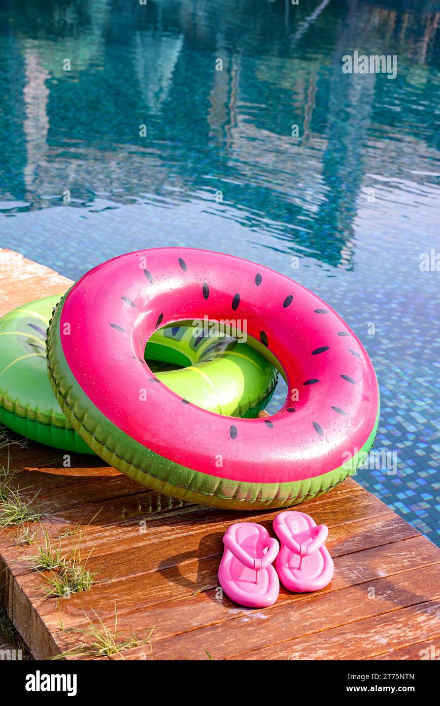 Inflatable rings and flip flops on wooden deck near swimming pool ...
