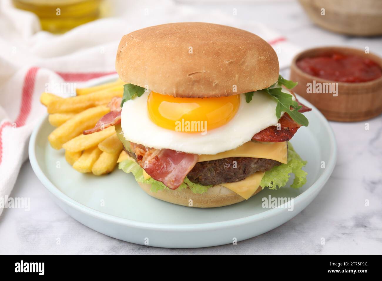 Delicious burger with fried egg and french fries served on white marble ...