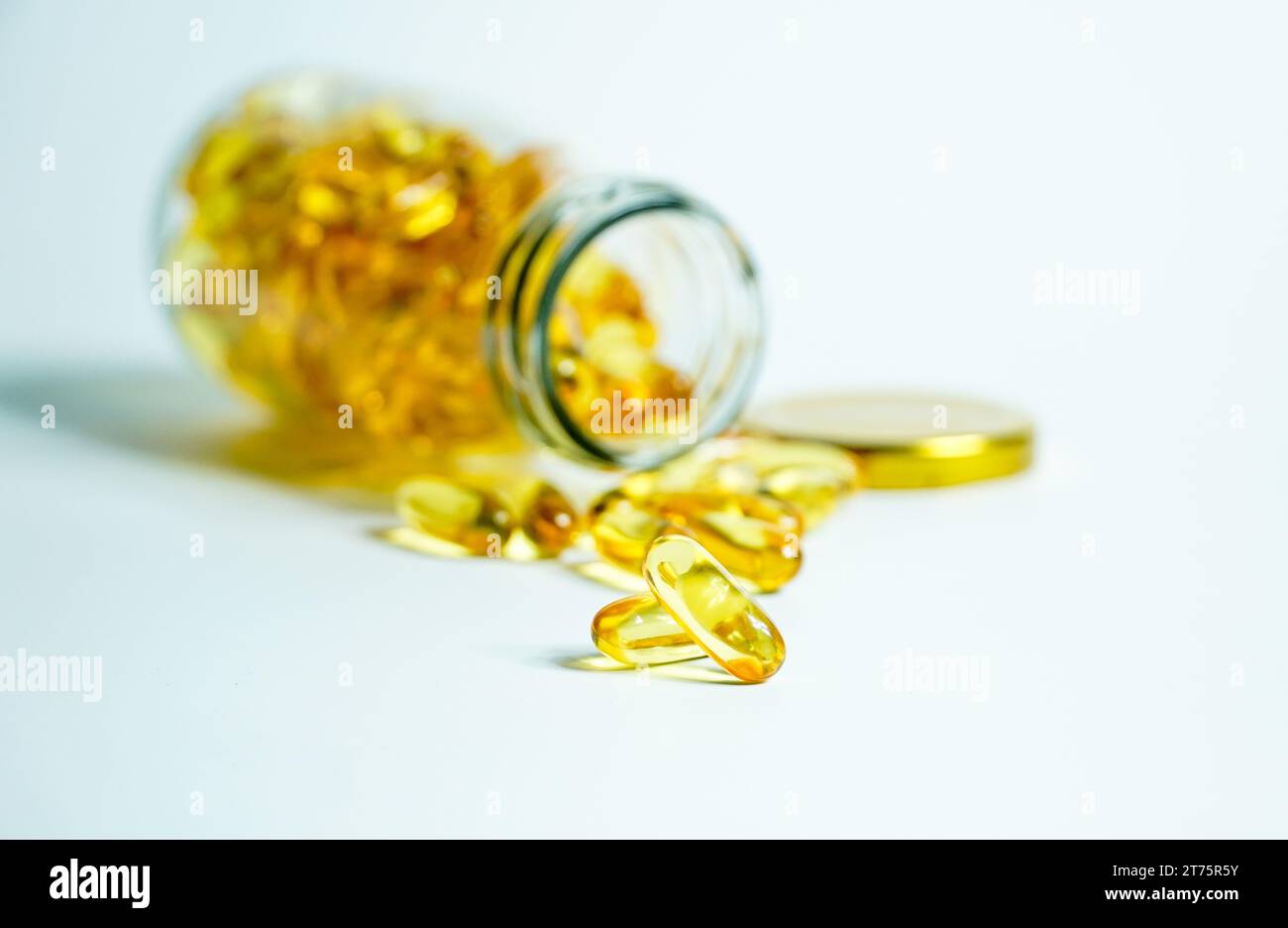 Fish Oil supplement capsules for health spill out from clear glass ...