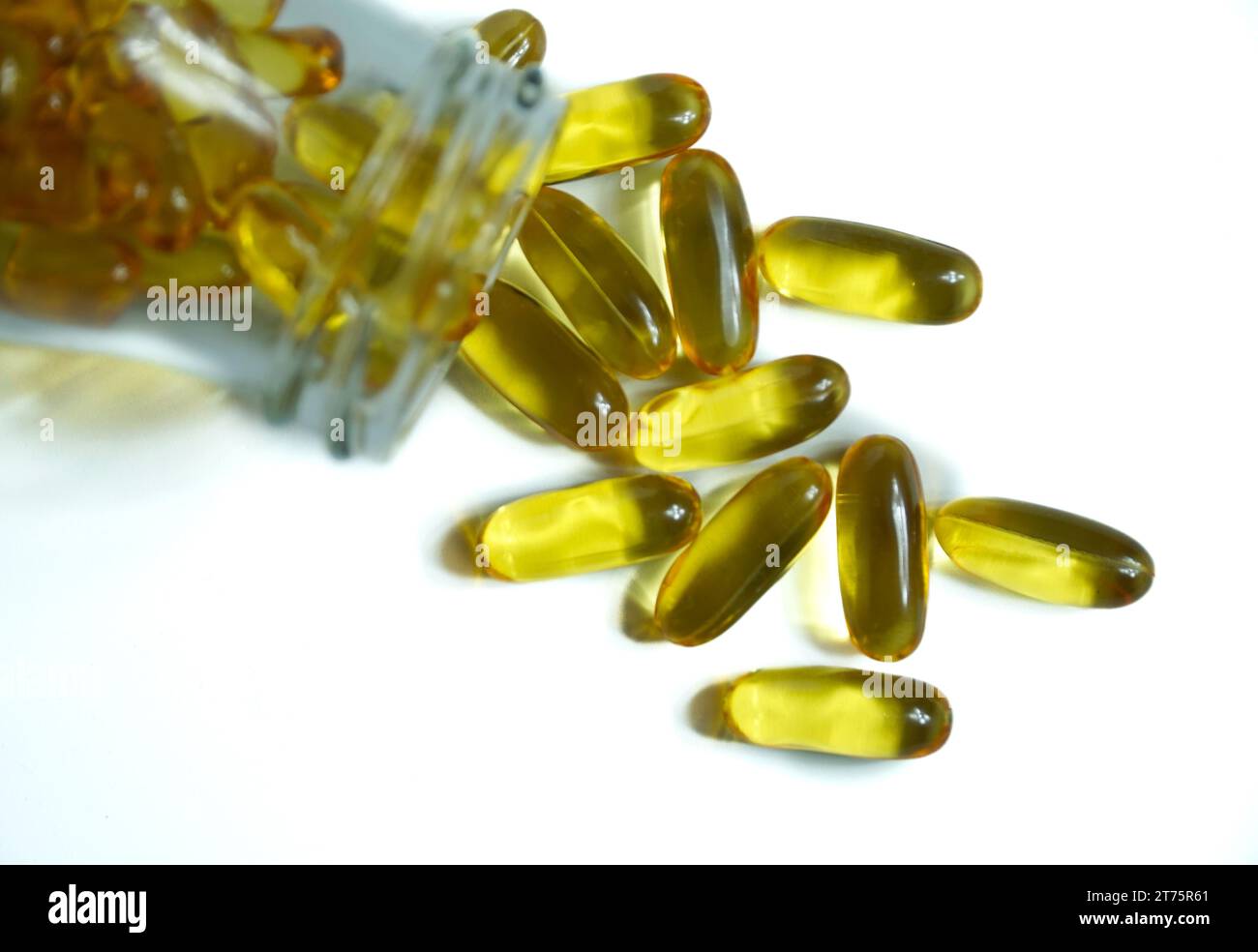 Fish Oil supplement capsules for health spill out from clear glass ...