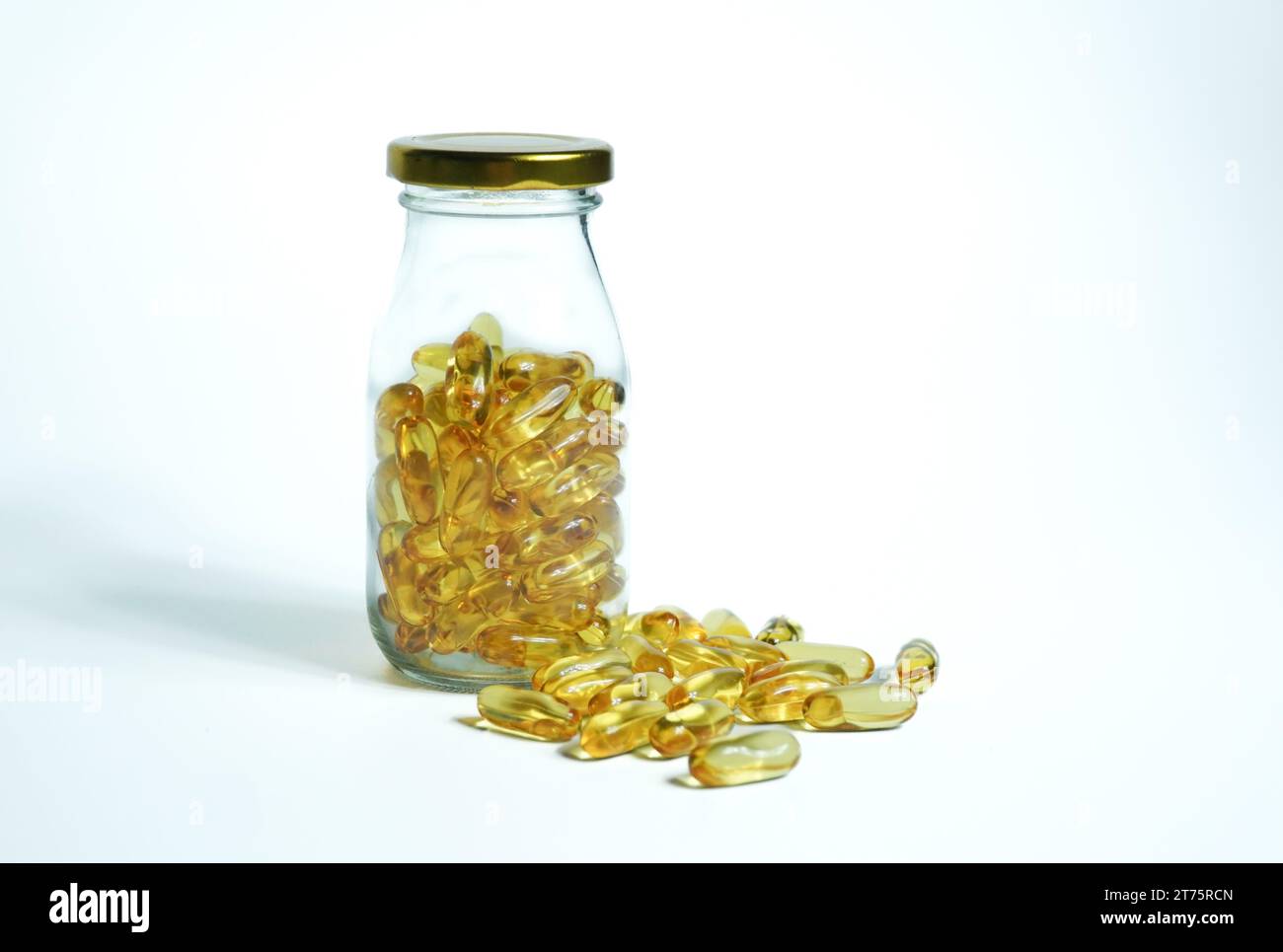 Fish Oil supplement capsules for health spill out from clear glass ...