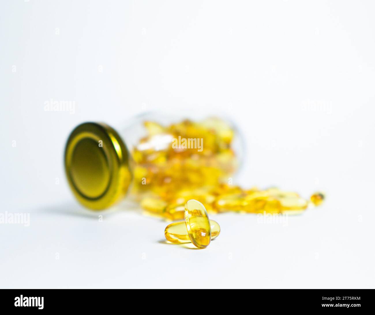 Fish Oil supplement capsules for health spill out from clear glass ...