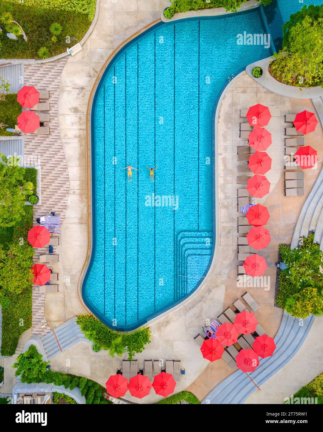 drone view from above at a couple swimming in an infinity pool on a ...