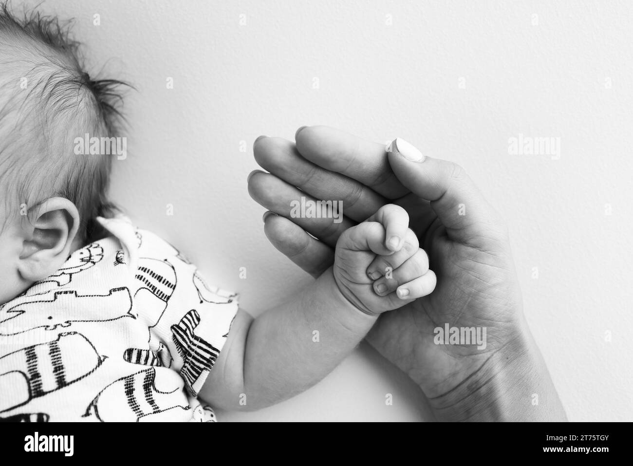 Parents' hands hold the fingers of newborn baby The hand of a mother ...