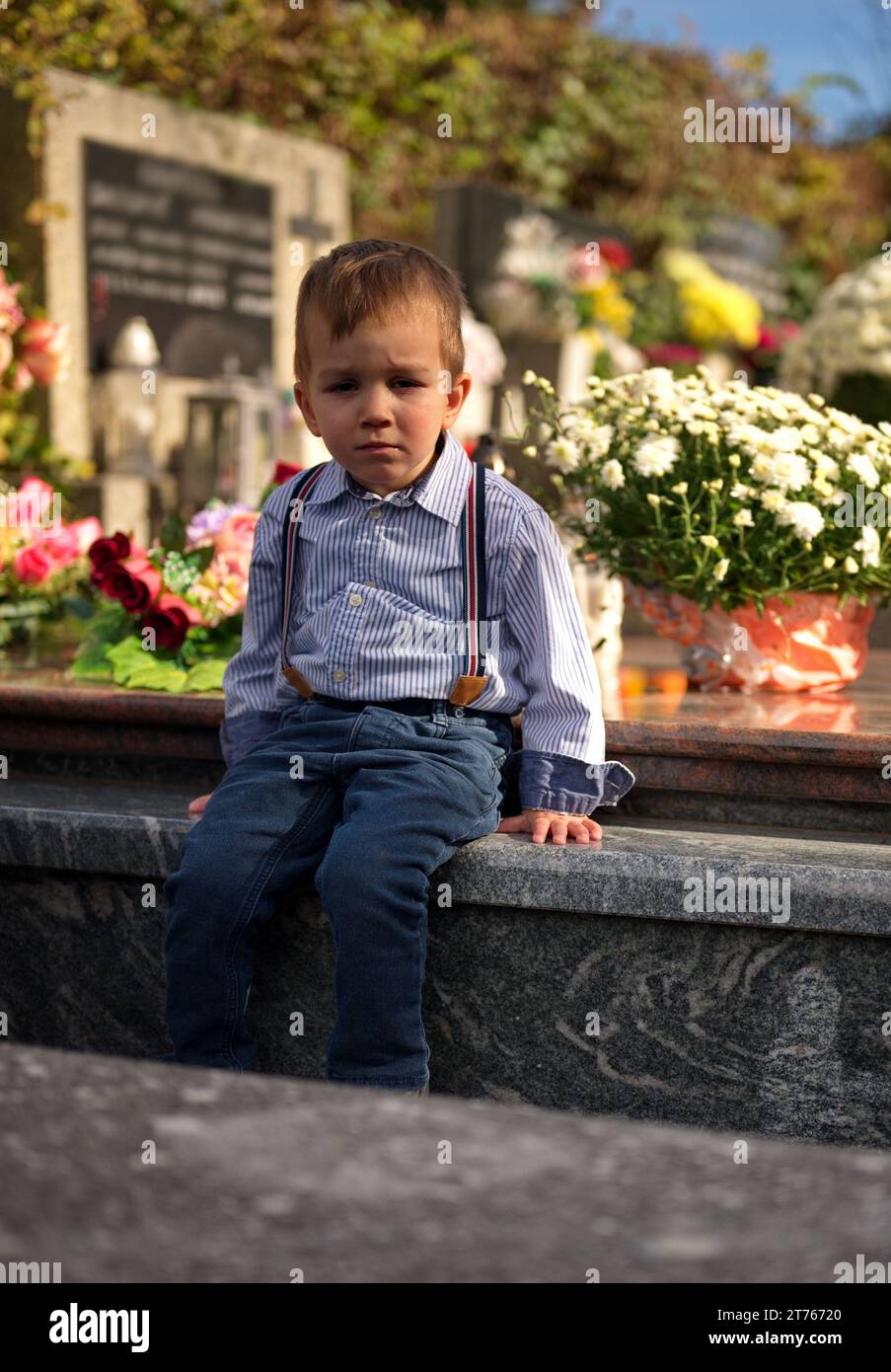 Little toddler sitting on a grave mourning Stock Photo - Alamy