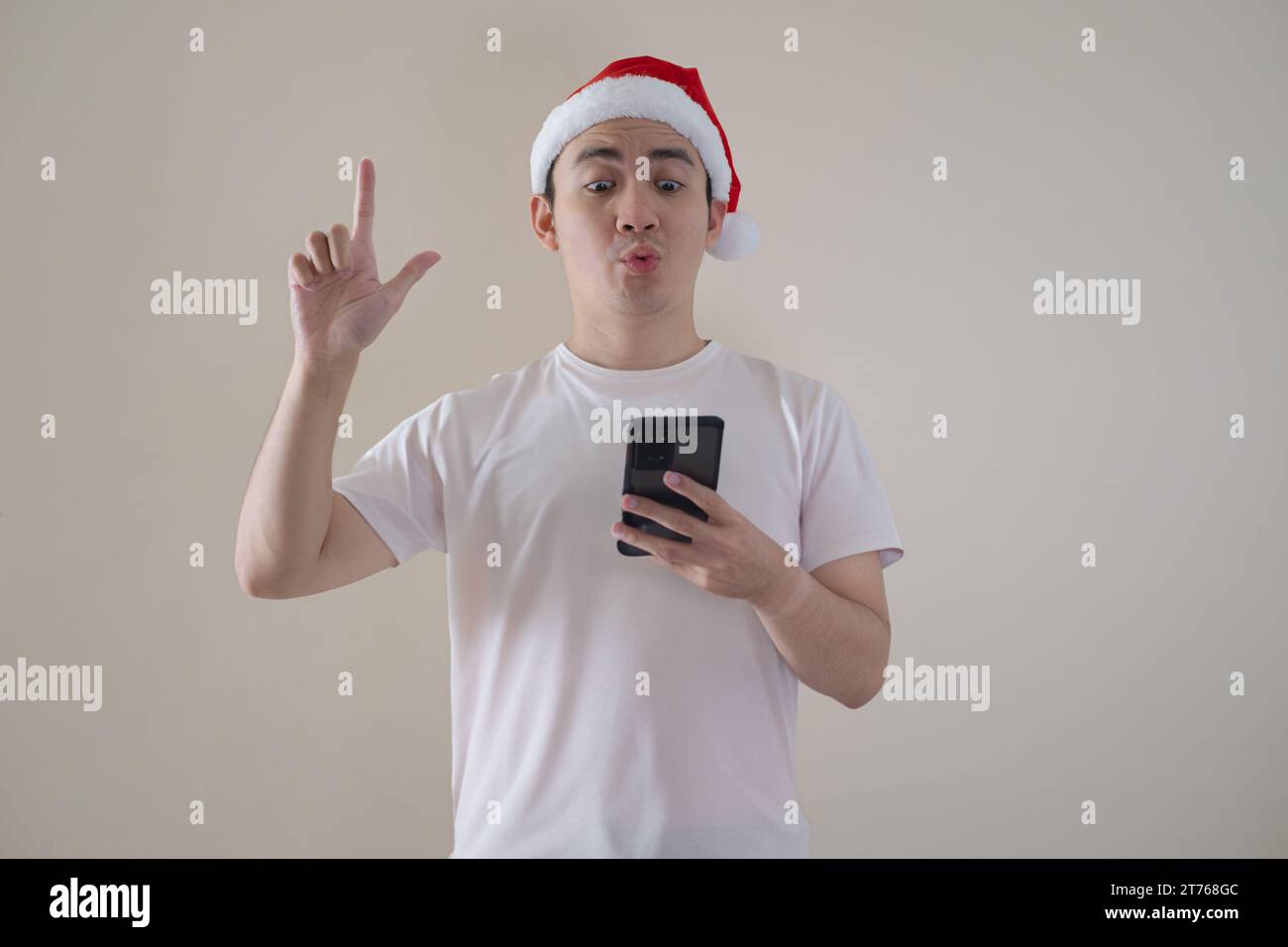 Young Asian Santa man is pointing upper right with shock face ...