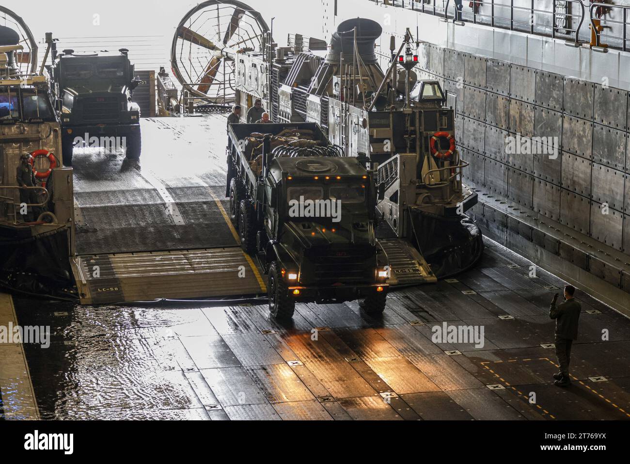 A U.S. Sailor guides a U.S. Marine Corps Medium Tactical Vehicle ...