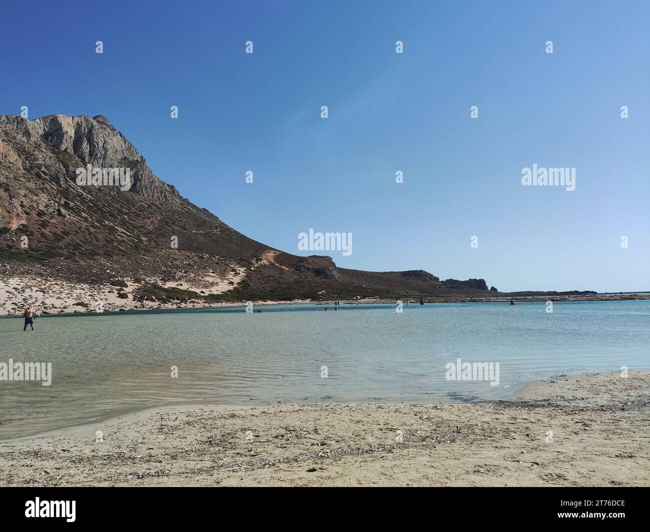 A crystal-clear view of the ocean at a beach, with a majestic mountain ...
