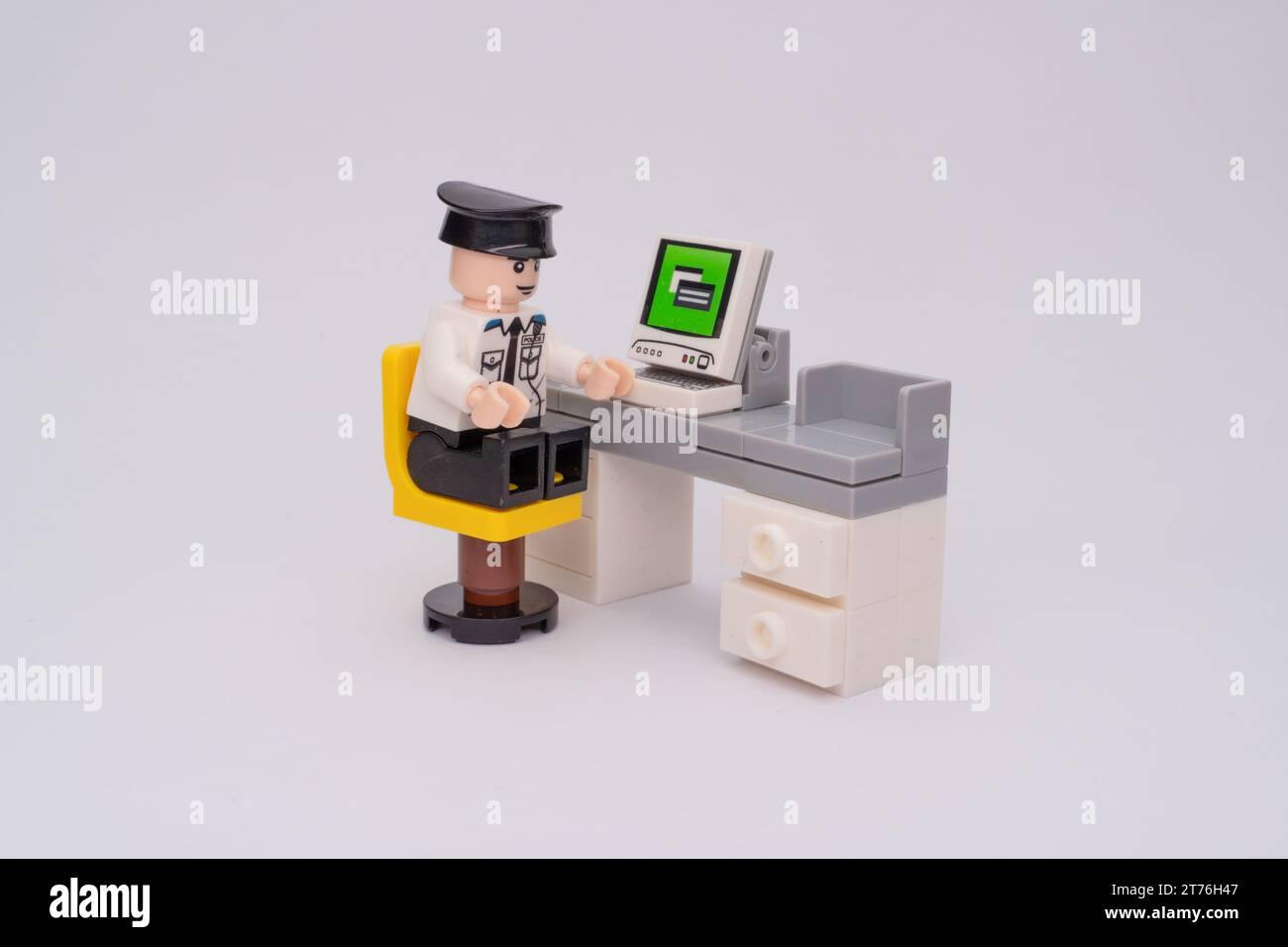 A miniature police officer figurine seated at a desk in front of a ...