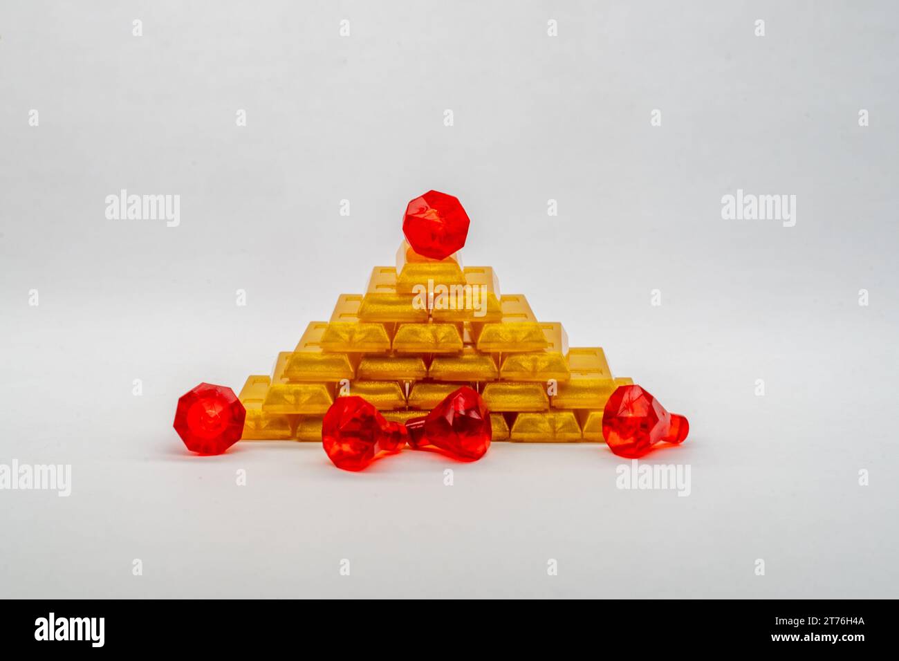 A stack of golden Lego blocks and red gems on a white background Stock ...